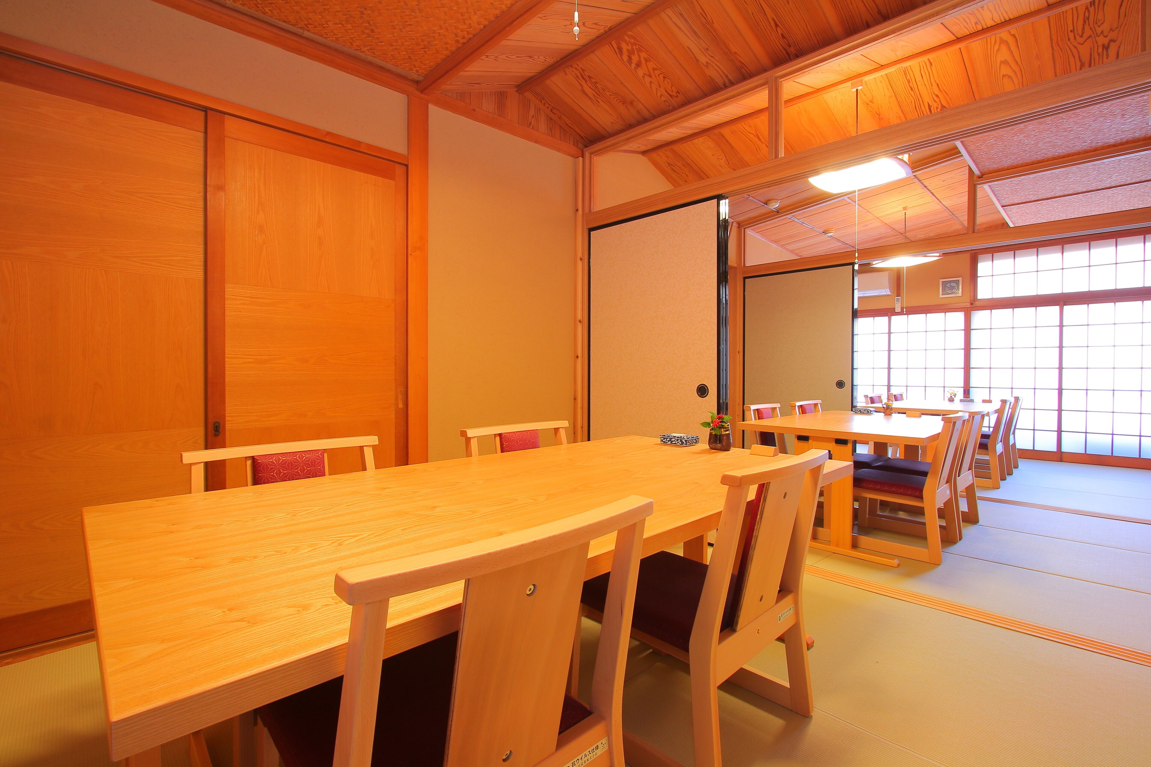 Um quarto japonês tradicional com tatames, portas deslizantes de madeira e uma mesa de madeira baixa com cadeiras.