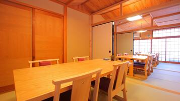 Um quarto japonês tradicional com tatames, portas deslizantes de madeira e uma mesa de madeira baixa com cadeiras.