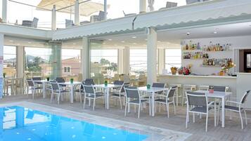 Uma área ao lado da piscina com assentos externos e um bar.
