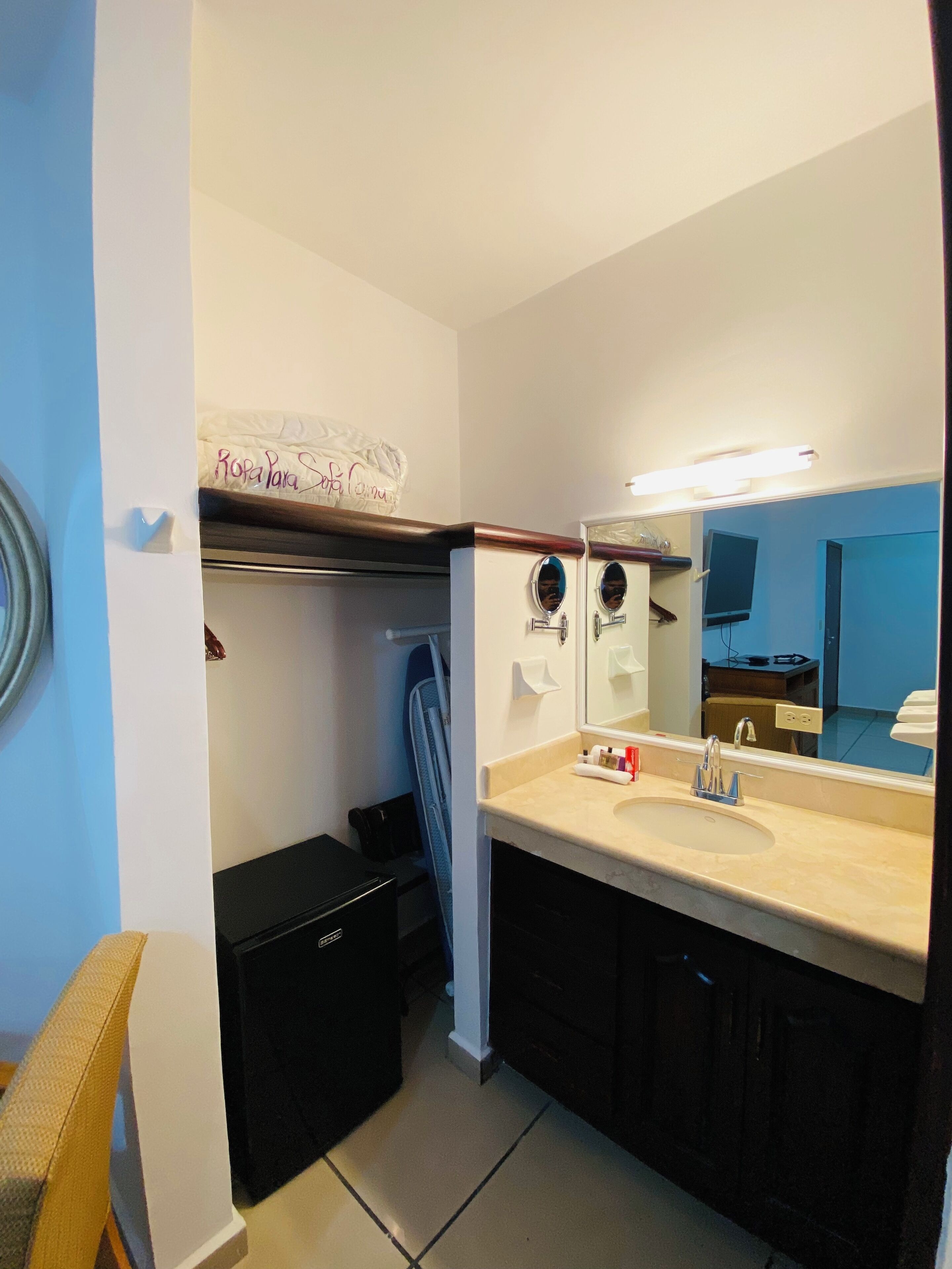Uma casa de banho compacta com lavatório, espelho e porta-toalhas.