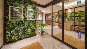 Um interior moderno com parede verde, móveis de madeira e porta de vidro que dá para outro cômodo.