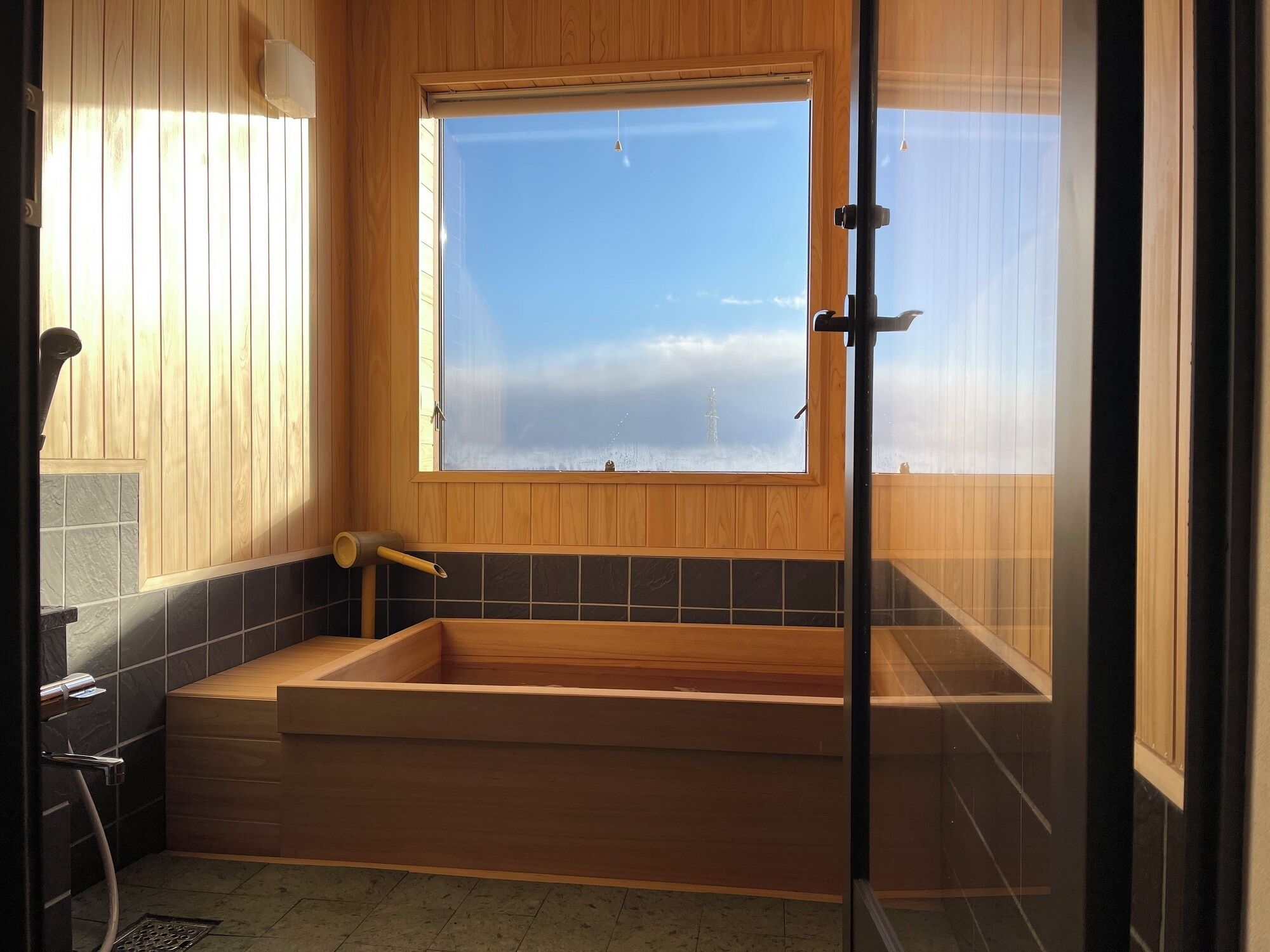 Uma casa de banho moderna com uma banheira de madeira, uma janela com vista e zona de duche.