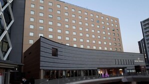 Um hotel moderno com muitas janelas e uma entrada curva.