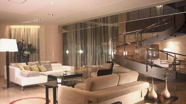 Uma sala de estar moderna com uma escada em espiral, um sofá branco, uma mesa de centro e uma janela grande com cortinas.