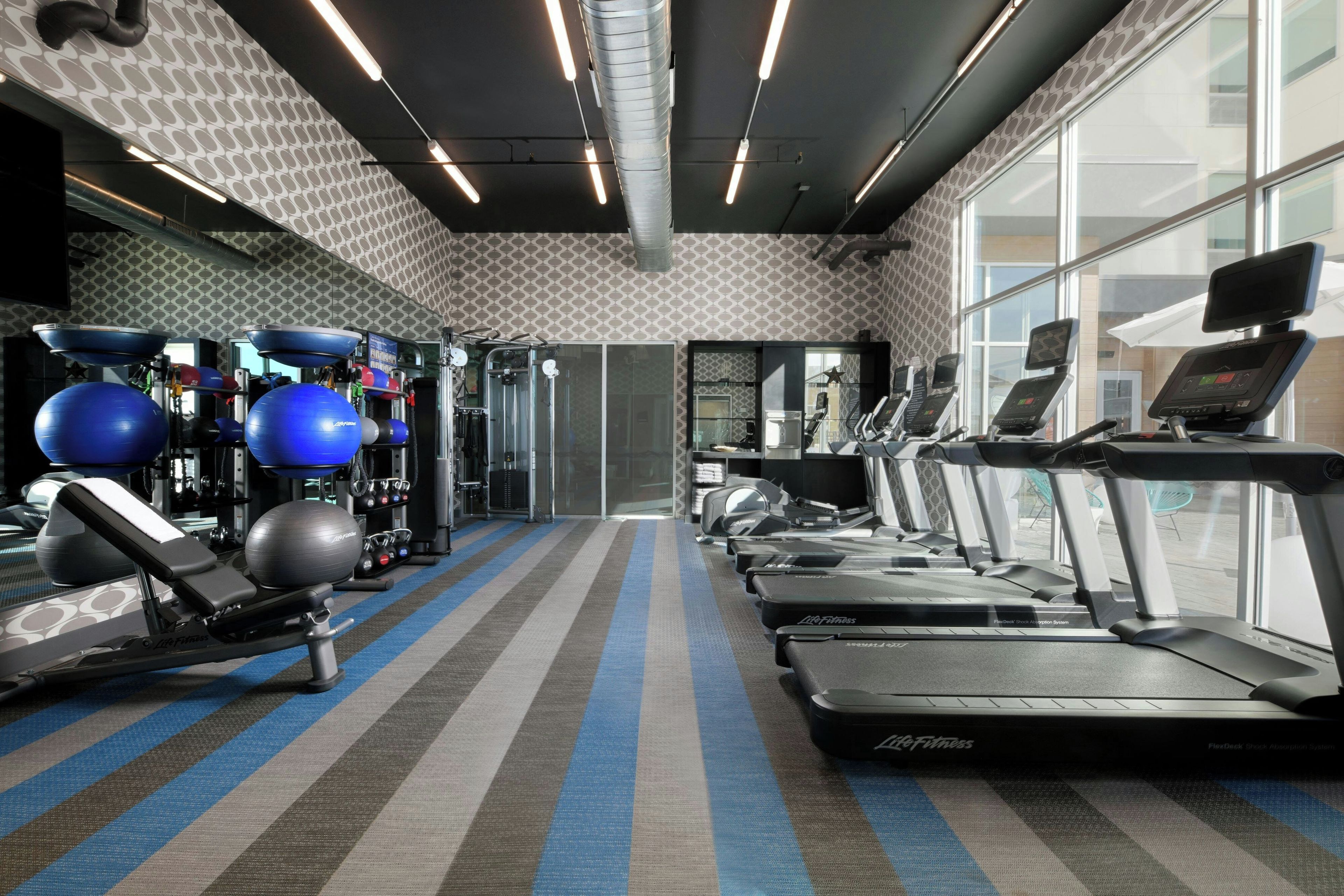 Academia com esteiras, bolas de exercício e aparelhos de musculação.
