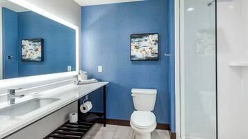 Uma casa de banho moderna com lavatório, sanita e chuveiro, tudo em branco.