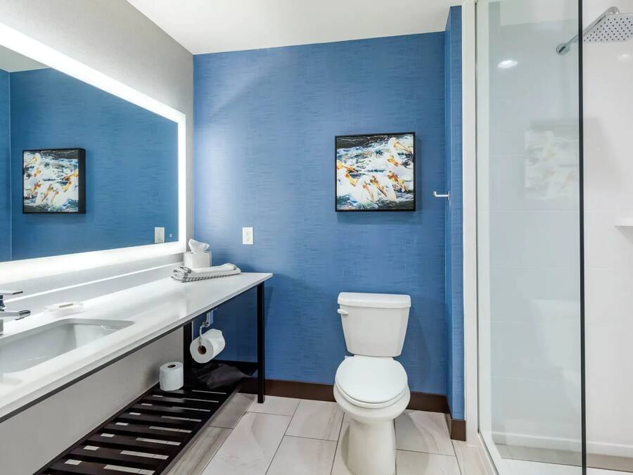 Uma casa de banho moderna com lavatório, sanita e chuveiro, tudo em branco.