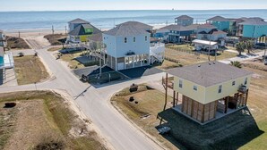 Uma área residencial costeira com casas, uma estrada e uma praia ao fundo.