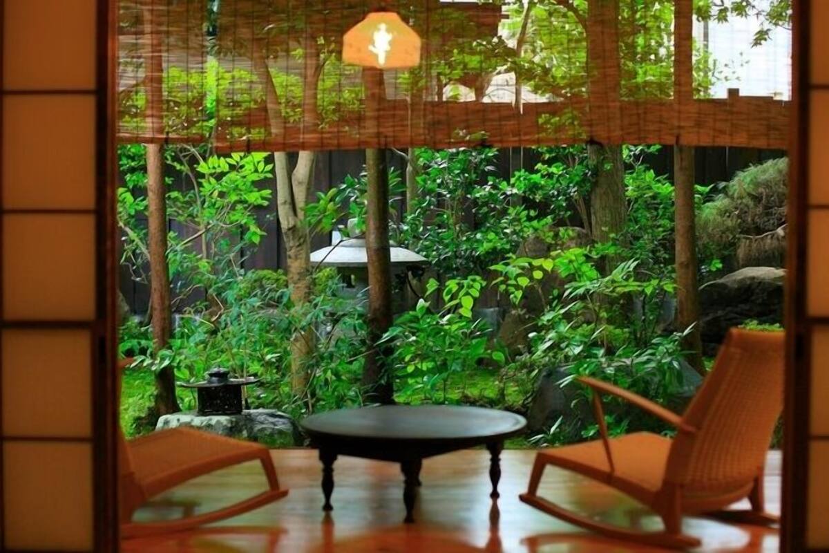 Quarto com vista para um jardim exuberante, uma mesa pequena e duas cadeiras de balanço.