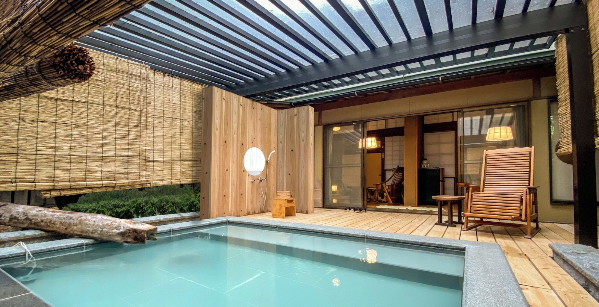Um deck de madeira com piscina, uma sauna de madeira e uma porta de vidro que dá para um espaço com cadeira e mesa.
