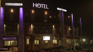Um hotel com uma placa 'HOTEL', uma placa 'RISTORANTE' e uma placa 'PIZZERIA'.