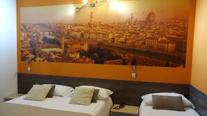 Quarto de hotel com duas camas, um grande mural da paisagem urbana na parede e uma mesa de cabeceira com um telefone.