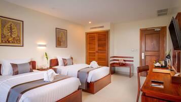 Quarto de hotel com duas camas, uma escrivaninha, uma cadeira, uma televisão e uma porta.