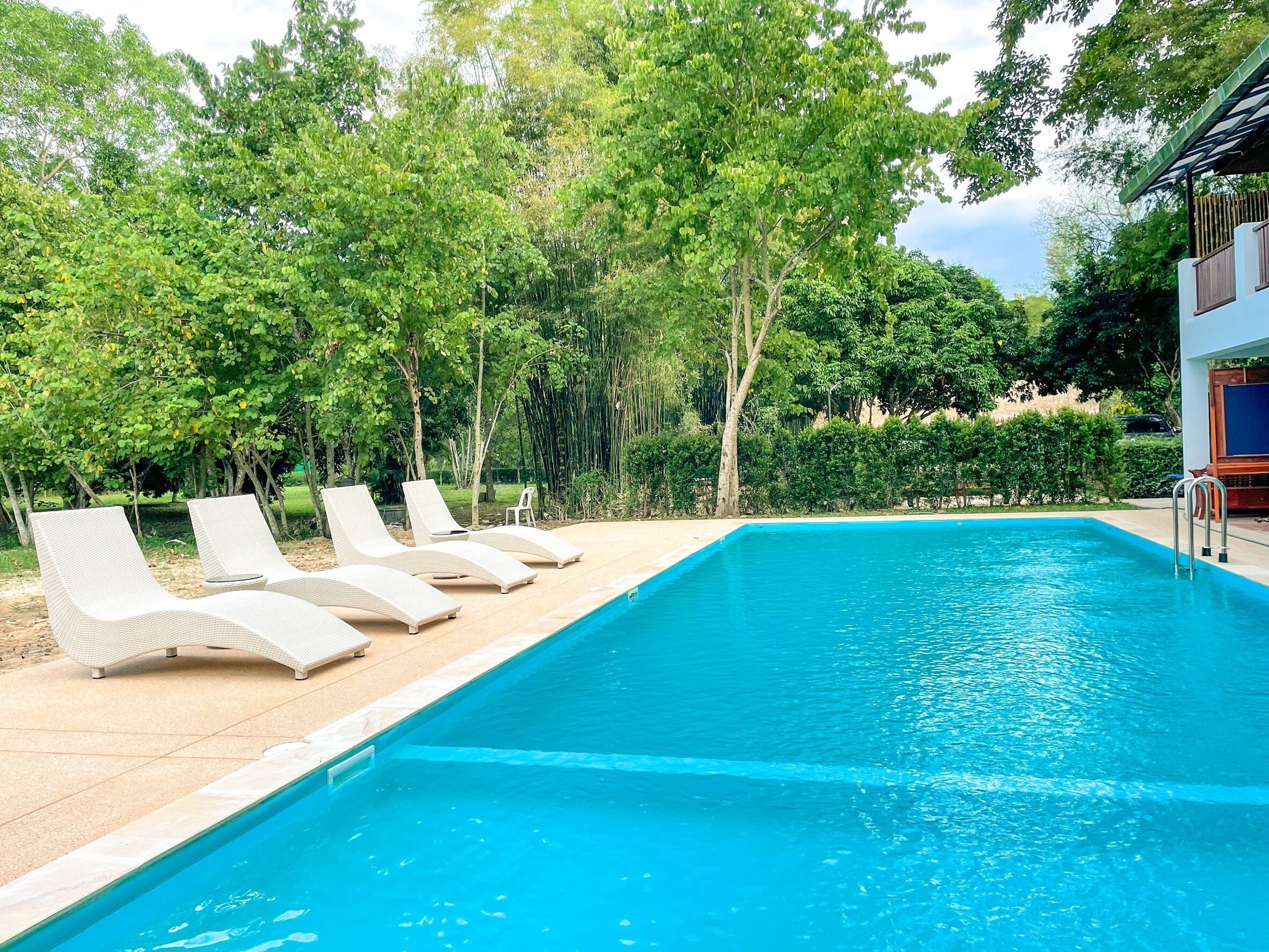 Piscina com cadeiras de sol brancas e águas azul cristalino.