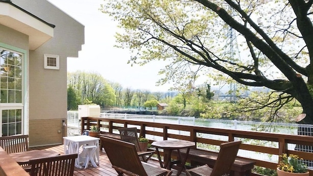 Um deck de madeira com móveis para área externa, vista para um lago e uma árvore.