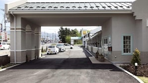 Uma área de estacionamento coberta com uma fileira de carros estacionados e um edifício com telhado em cerâmica.