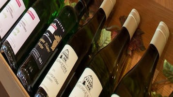 Uma estante de madeira com várias garrafas de vinho, cada uma com etiqueta indicando a marca e o ano.