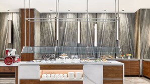Uma cozinha moderna com painel de mármore, ilha central com estrutura de vidro e uma máquina de café.