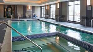 Piscina interna com água cristalina, bordas azulejadas e uma cadeira de salva-vidas. Há espreguiçadeiras e um aviso indicando que não há salva-vidas de serviço.