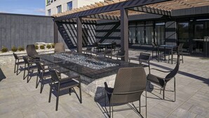 Um pátio externo com lareira, área de estar e estrutura de pérgola.