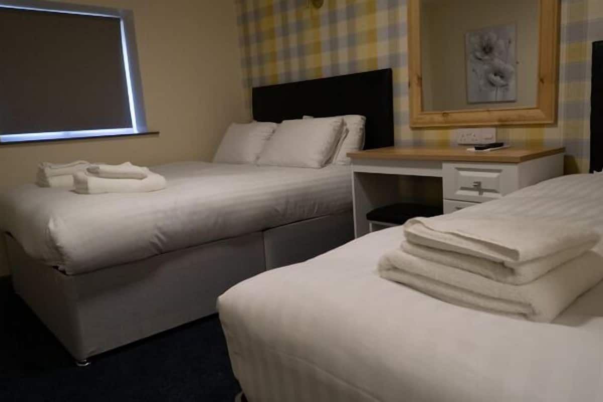 Quarto de hotel com duas camas, uma escrivaninha e uma cadeira.