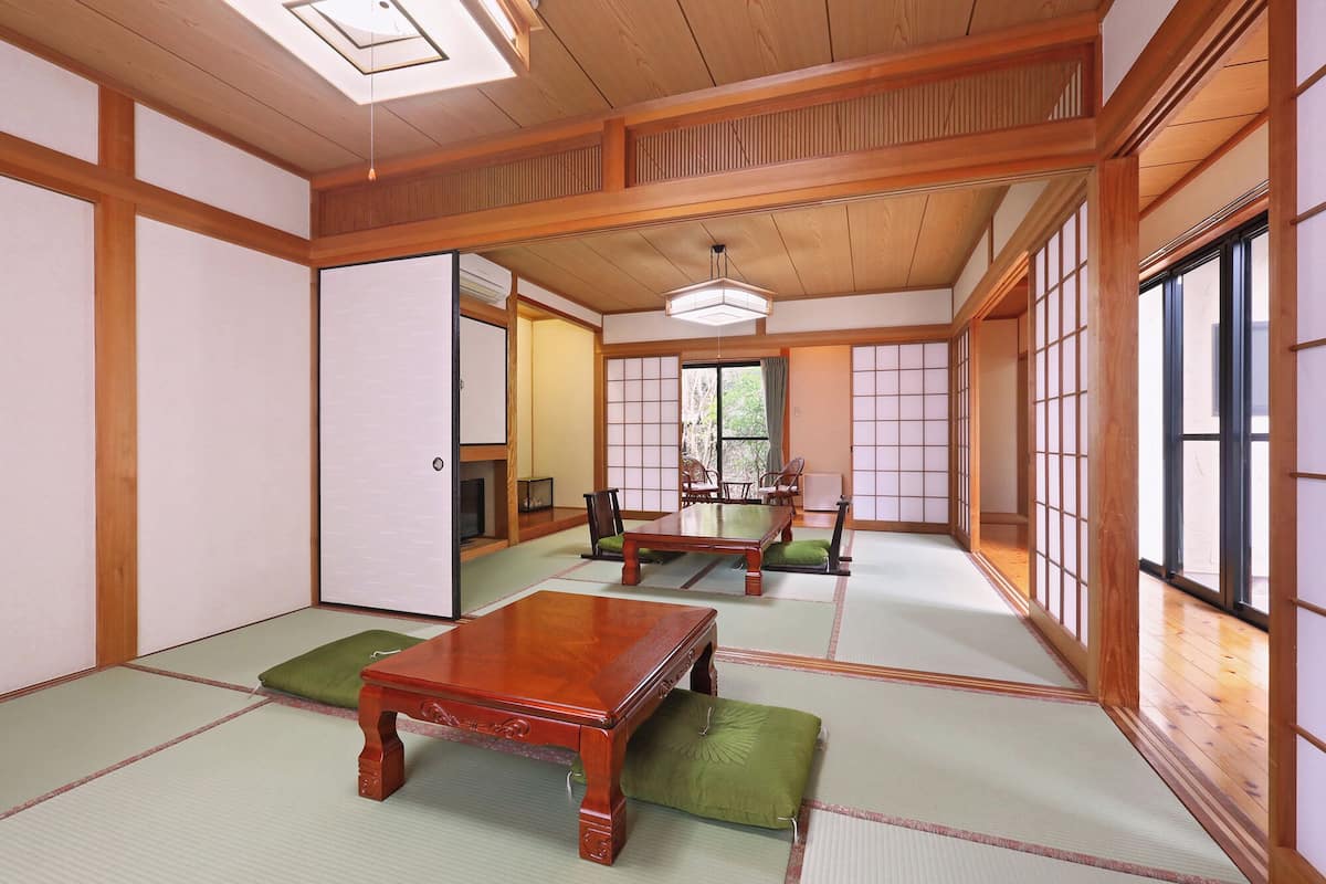 Um quarto japonês tradicional com tatames, uma mesa de madeira e portas deslizantes.