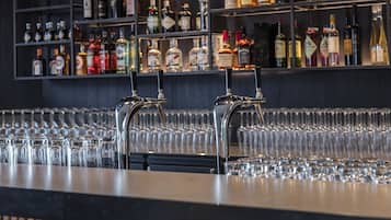 Uma área de bar com duas torneiras e uma fileira de copos.