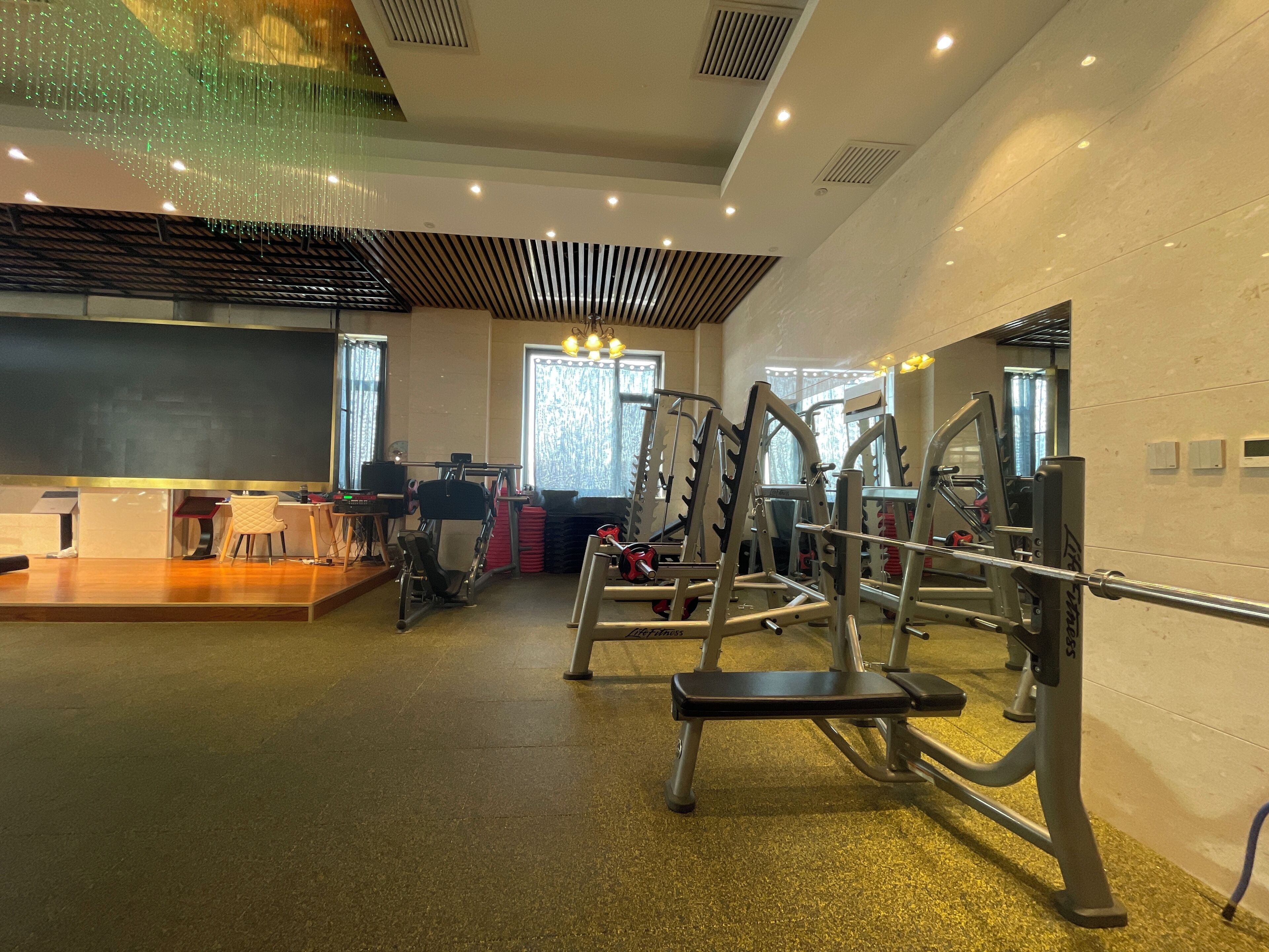 Uma academia com equipamentos de ginástica, um quadro negro e uma mesa com um computador.