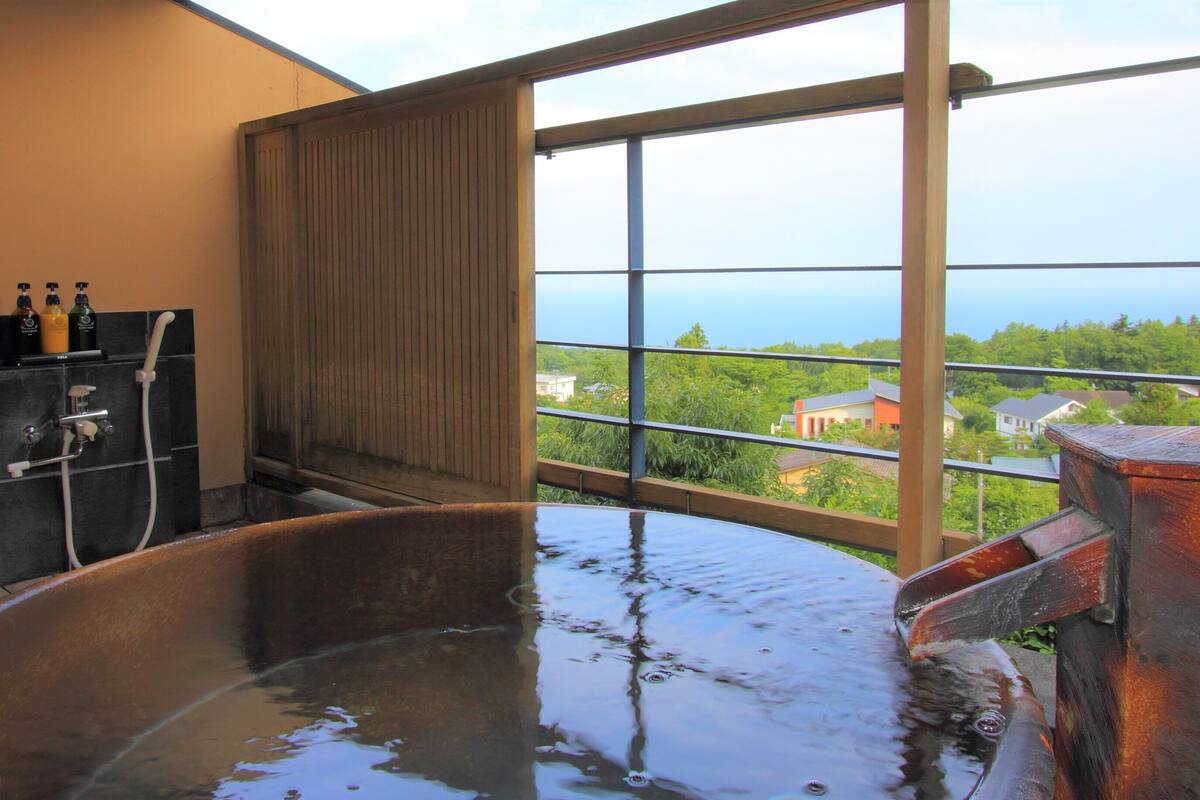 Uma banheira de hidromassagem com vista para o oceano e uma varanda com guarda-corpo de madeira.
