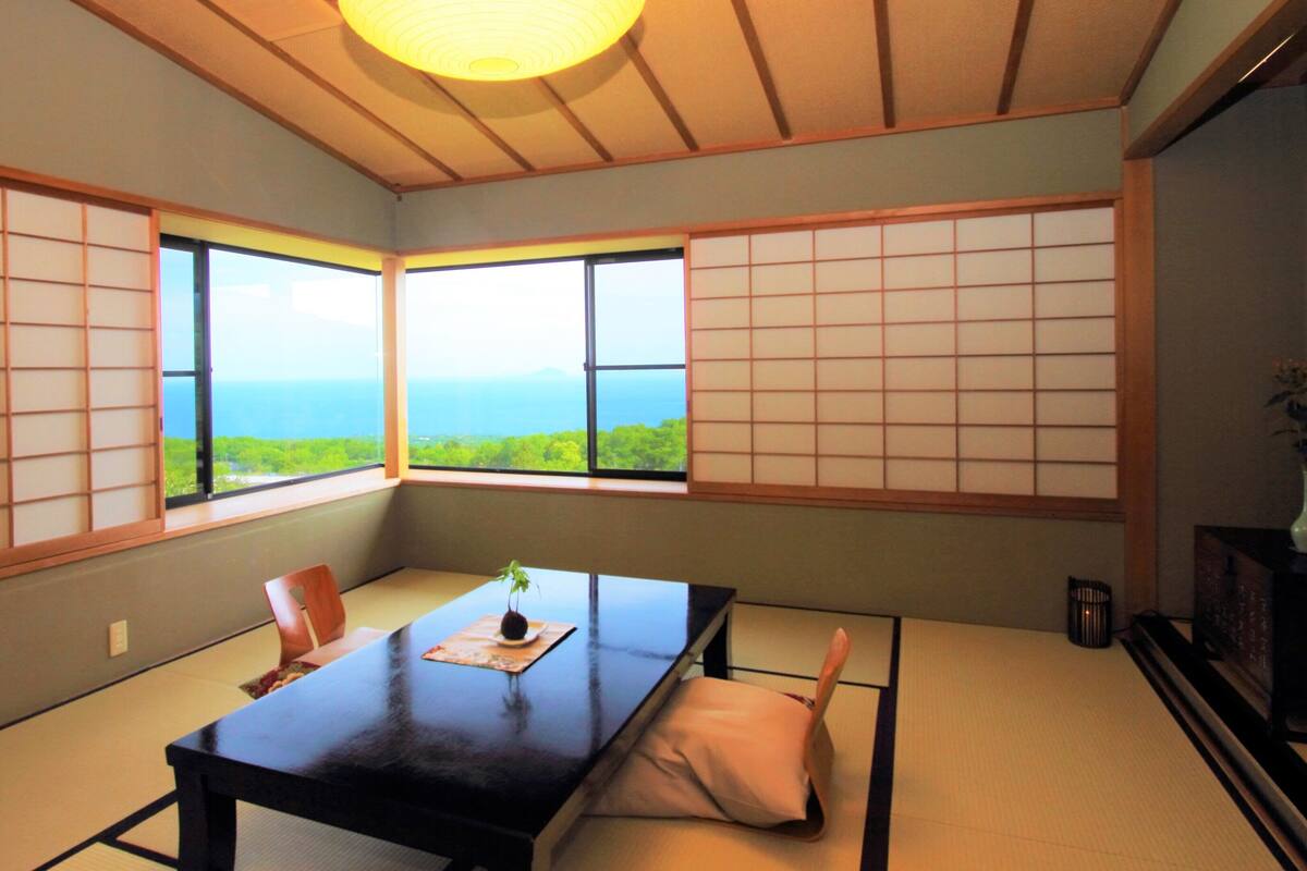 Um quarto japonês tradicional com tatames, uma mesa baixa e biombos shoji.