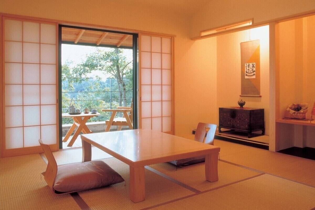 Um quarto japonês tradicional com tatames, uma mesa baixa, um sofá e portas deslizantes.