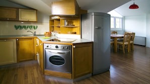 Uma cozinha compacta com armários de madeira, forno embutido e geladeira.