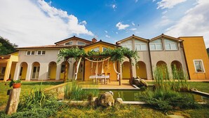 Um edifício de dois andares com um pátio, piscina e pérgola com mesa e cadeiras.