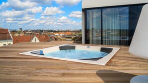 Terraço com hidromassagem, deck de madeira e vista para a paisagem urbana.
