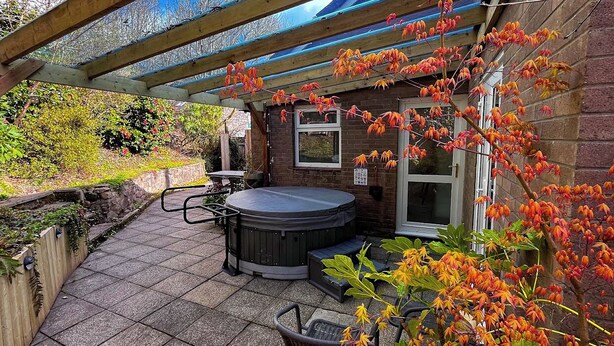 Um pátio com hidromassagem, área de estar externa e pérgola.