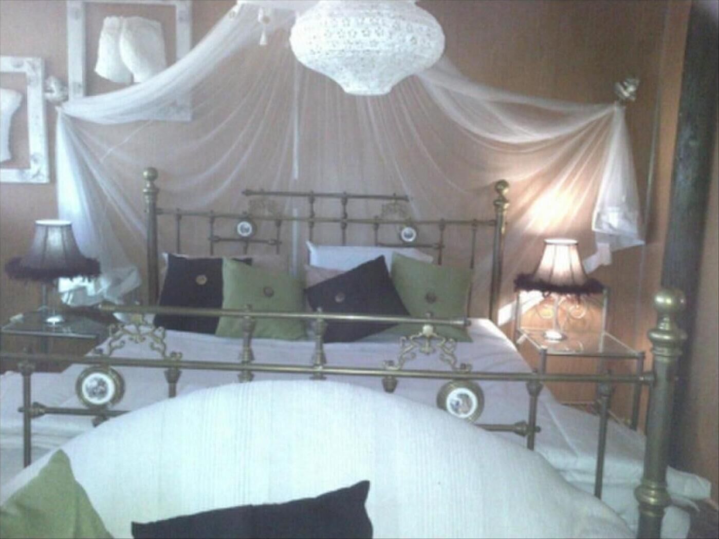 Cama com dossel, abajures e mesa de cabeceira.