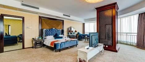 Quarto de hotel com uma cama, uma escrivaninha, uma televisão e uma janela grande.