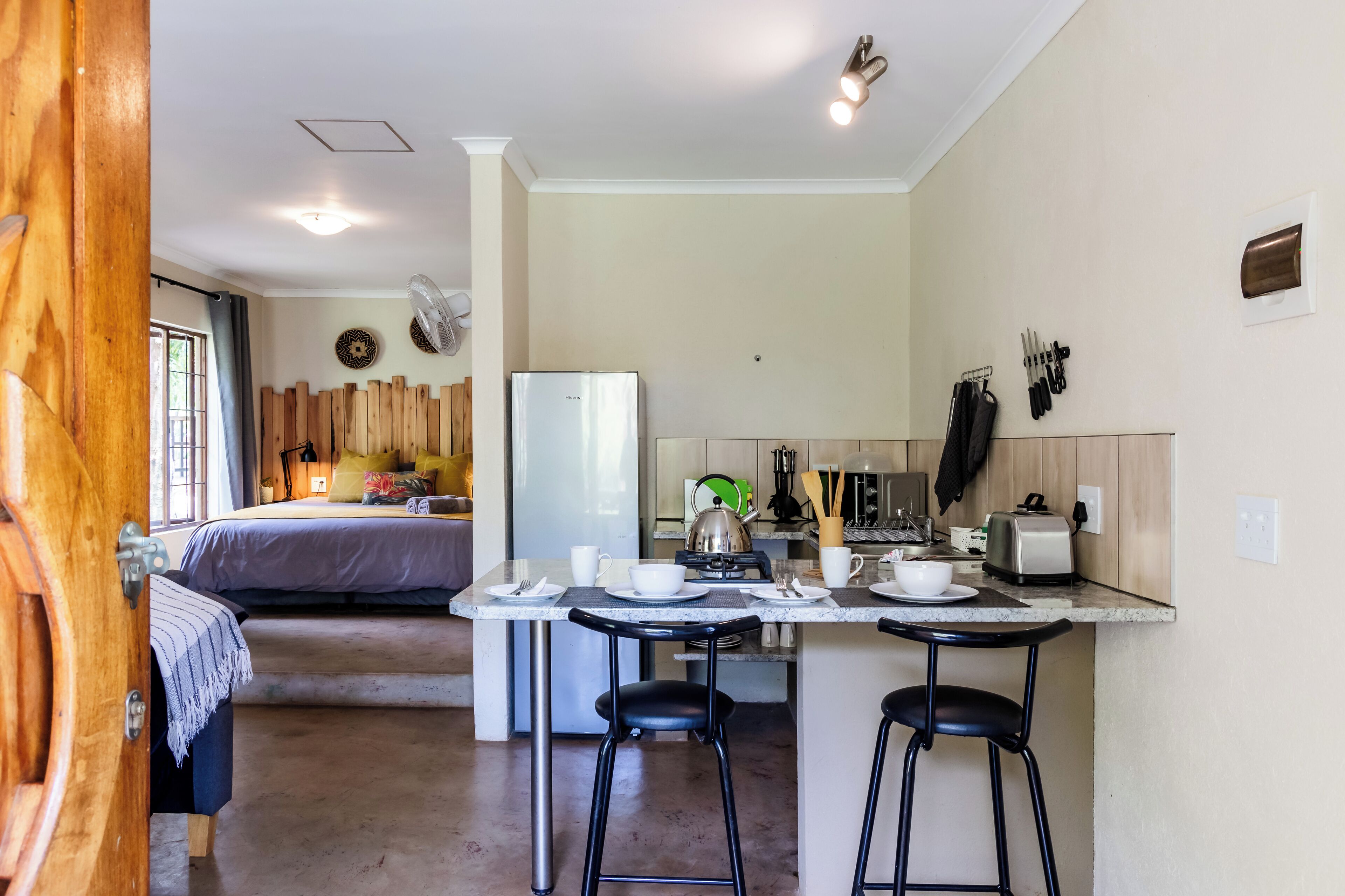 Cozinha compacta com geladeira, fogão e banquetas de bar.