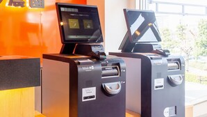 Quiosque de autoatendimento com tela digital e leitor de cartão, provavelmente para registo de hóspedes ou informações.