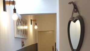 Um corredor com piso de madeira, uma porta no fim e luminárias fixadas na parede.