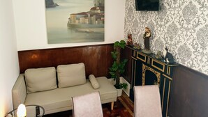Uma sala de estar com um sofá, uma televisão, uma lareira decorativa e um quadro na parede.