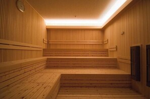 Uma sauna com bancos e degraus de madeira, um relógio na parede e uma porta de madeira.