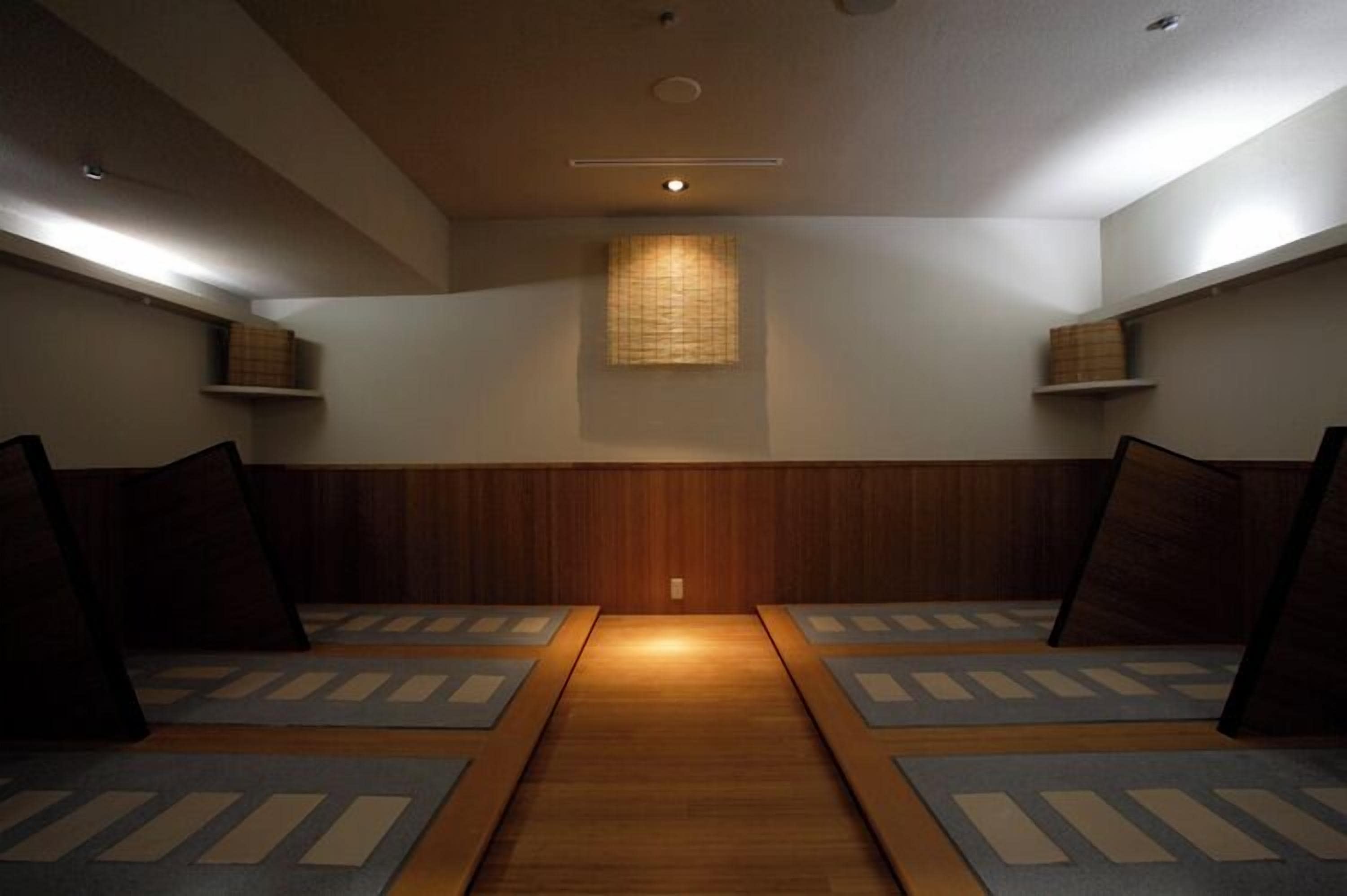 Um quarto com soalho de madeira central, duas paredes com lambris e uma luminária no teto.