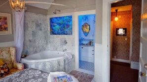 Quarto com uma cama grande, banheira e área de chuveiro.