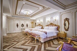 Um quarto luxuoso com uma cama grande, móveis elaborados e um piso em padrão herringbone.