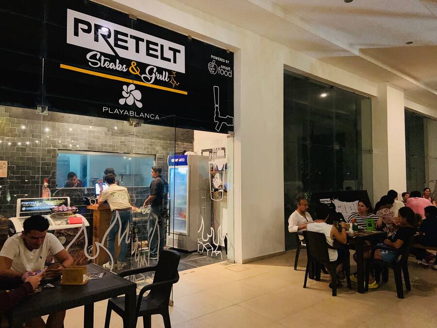 Restaurante PRETELT Steaks & Grill com uma placa em preto e branco, um logotipo Playblanca e uma máquina de sorvete com a marca.
