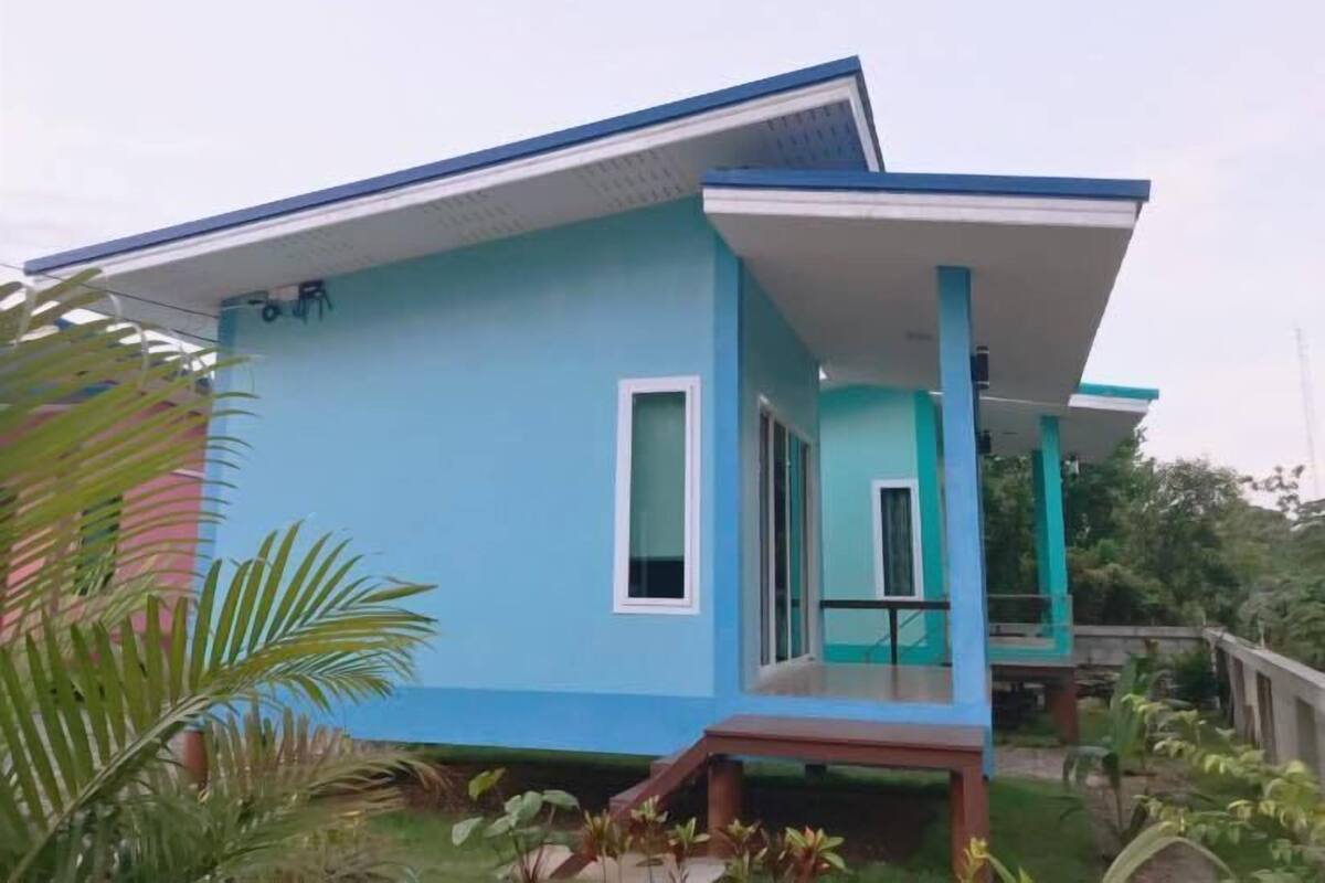 Um edifício de dois andares com fachada azul e um pequeno alpendre.