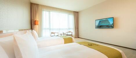 Quarto de hotel com duas camas, uma televisão na parede e uma janela com cortinas.