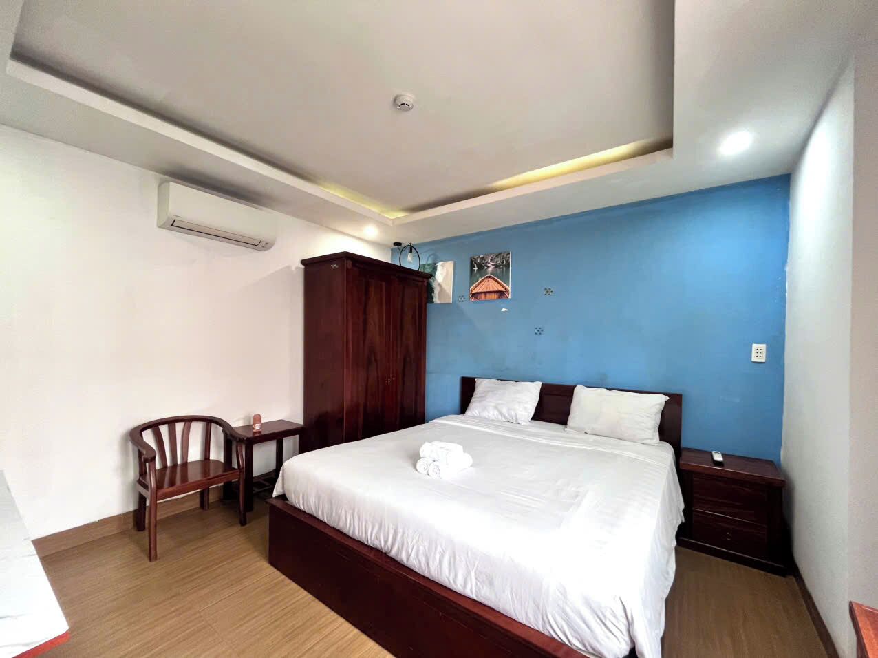 Quarto de hotel com cama, escrivaninha, cadeira e guarda-roupa.