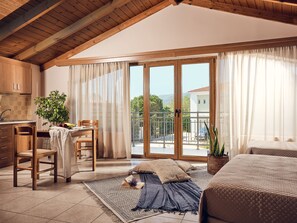 Um quarto acolhedor com teto de madeira, área de jantar com mesa e cadeiras, cama e varanda com vista para o campo.